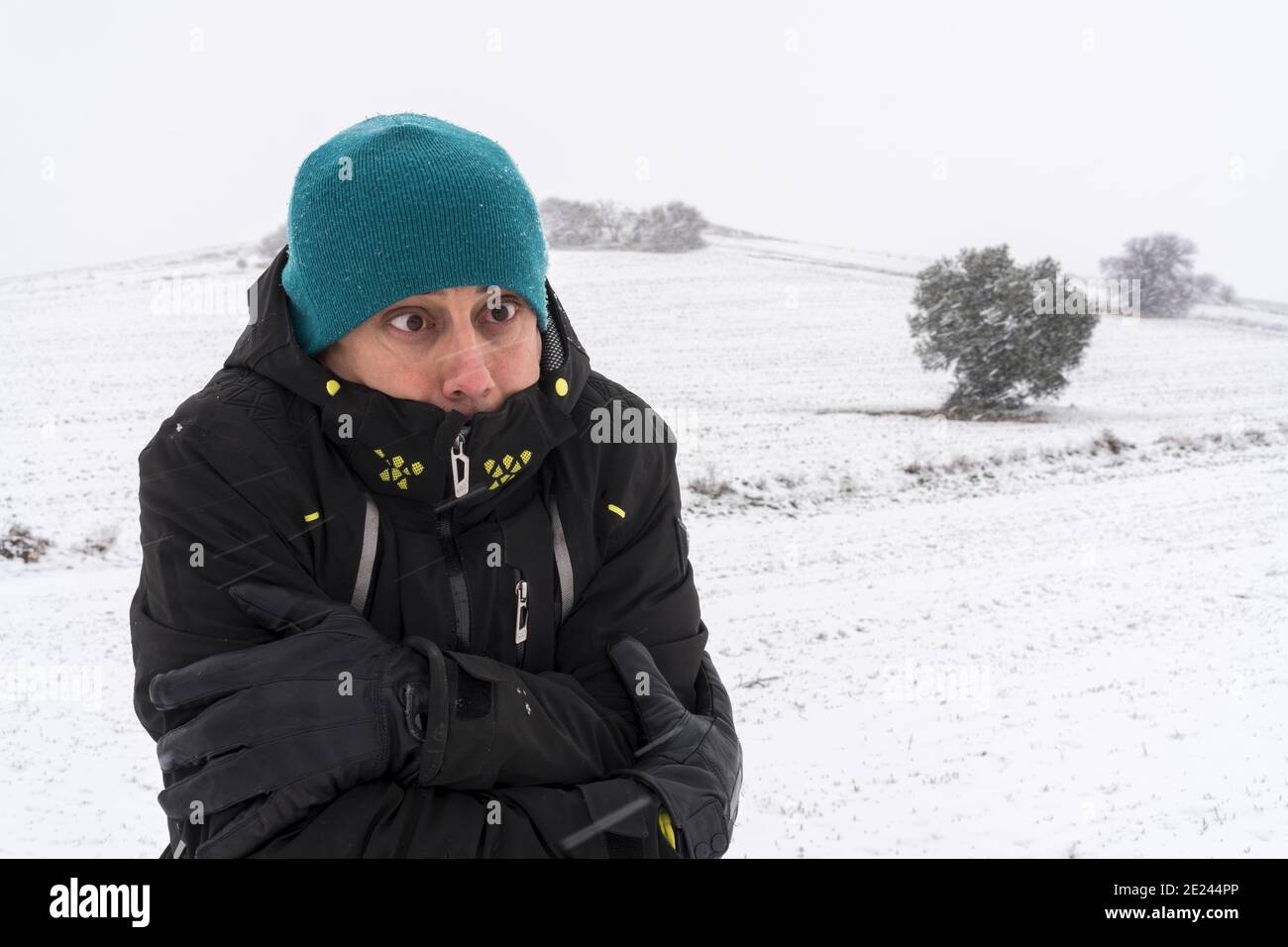 Very cold man with coat, hat and gloves, in the middle of a snowfall ...