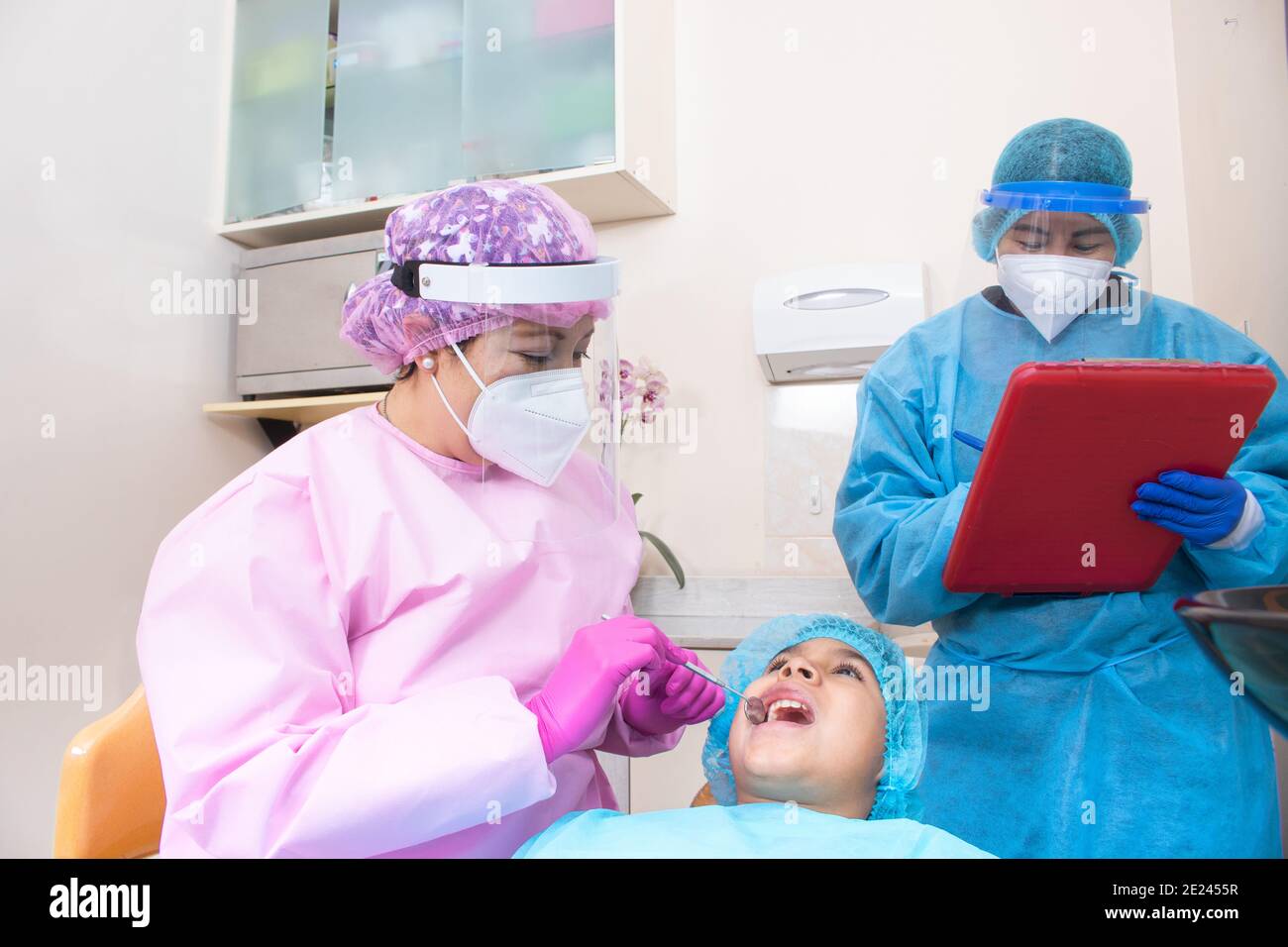 Horizontal shot of a female dentist in double protective masks working ...