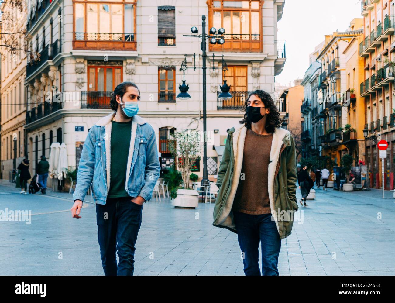 Selective focus shot of two men in facial masks walking through the ...