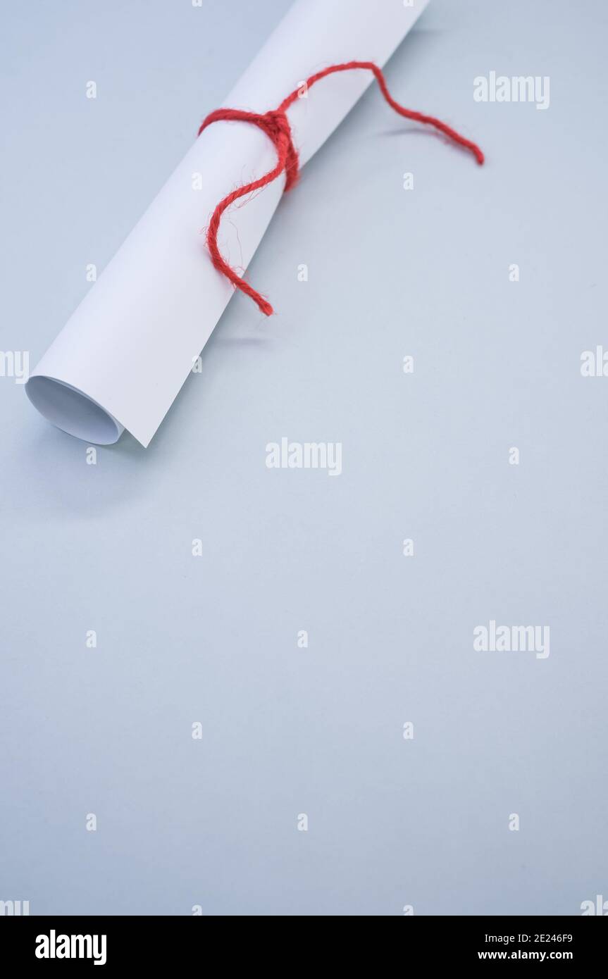 Vertical shot of a white paper scroll tied with red thread isolated on ...