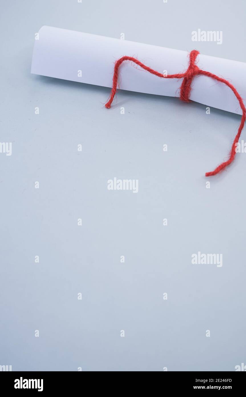 Vertical shot of a white paper scroll tied with red thread isolated on ...