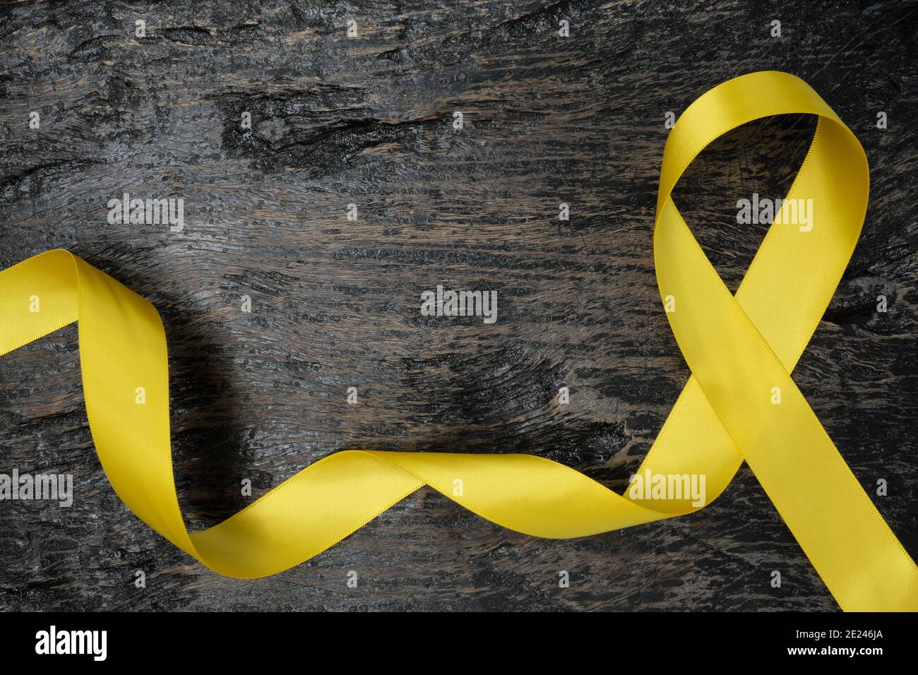 Top view of yellow ribbon on dark wood background with copy space ...