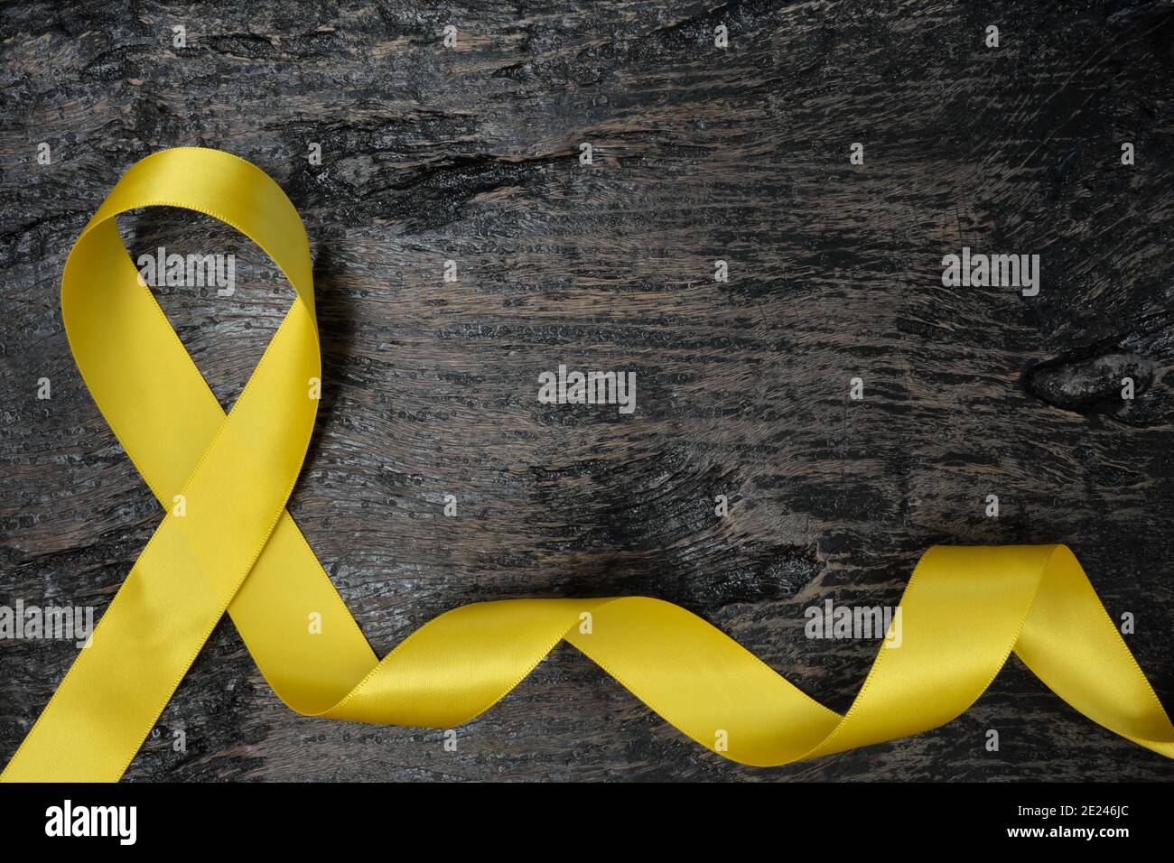 Top view of yellow ribbon on dark wood background with copy space ...