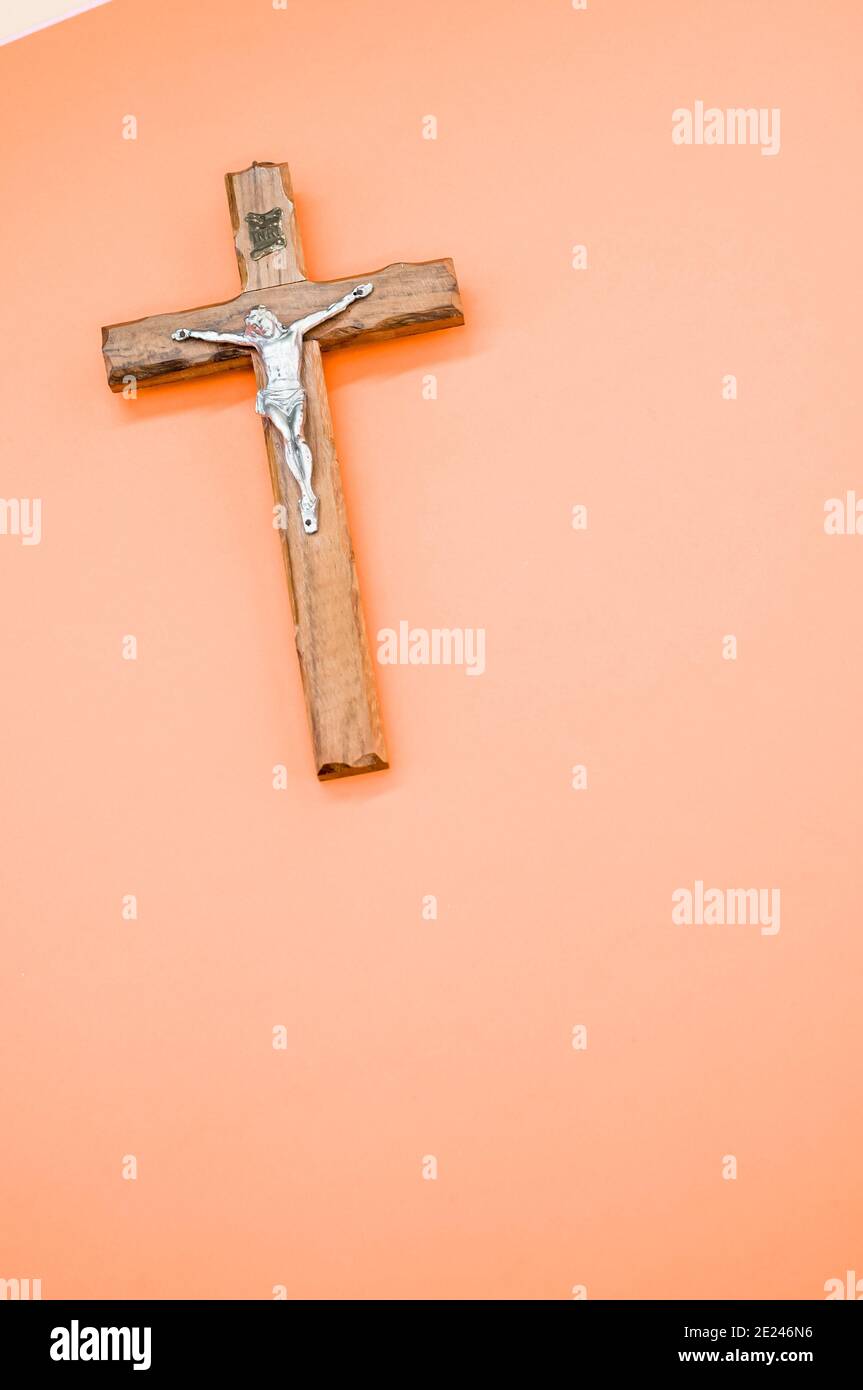 Vertical shot of a wooden crucifixion of Christ cross on a pastel peach ...