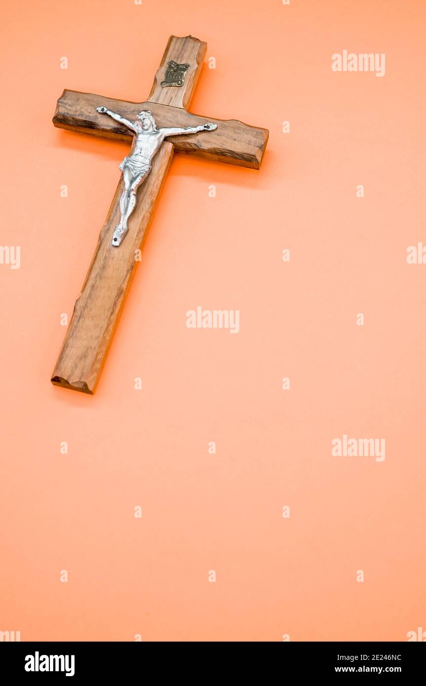 Vertical shot of a wooden crucifixion of Christ cross on a pastel peach ...