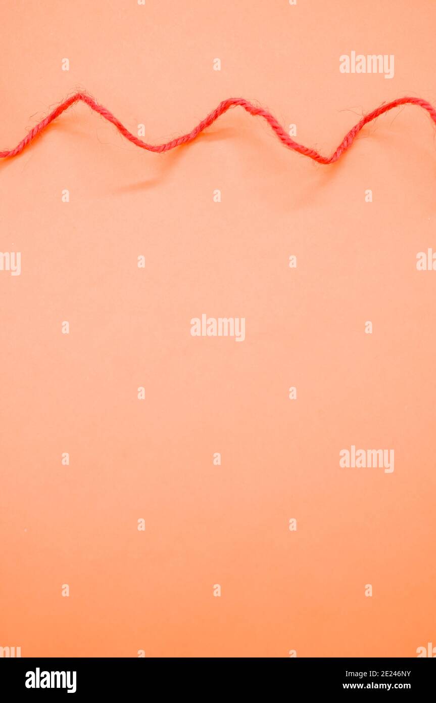 Vertical shot of a bright red thread on a peach background Stock Photo ...