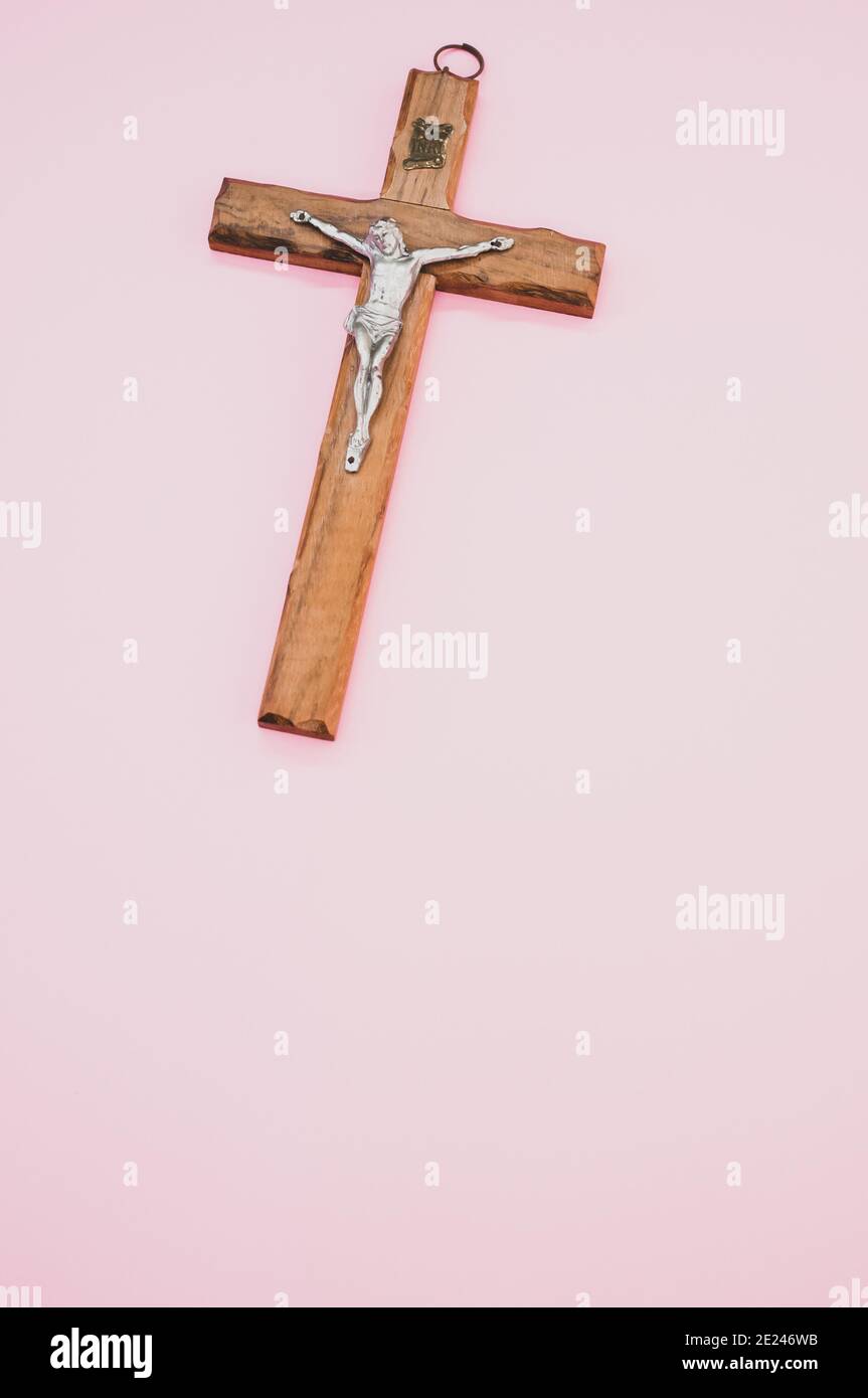 Vertical shot of a wooden crucifixion of Christ cross on a pink ...
