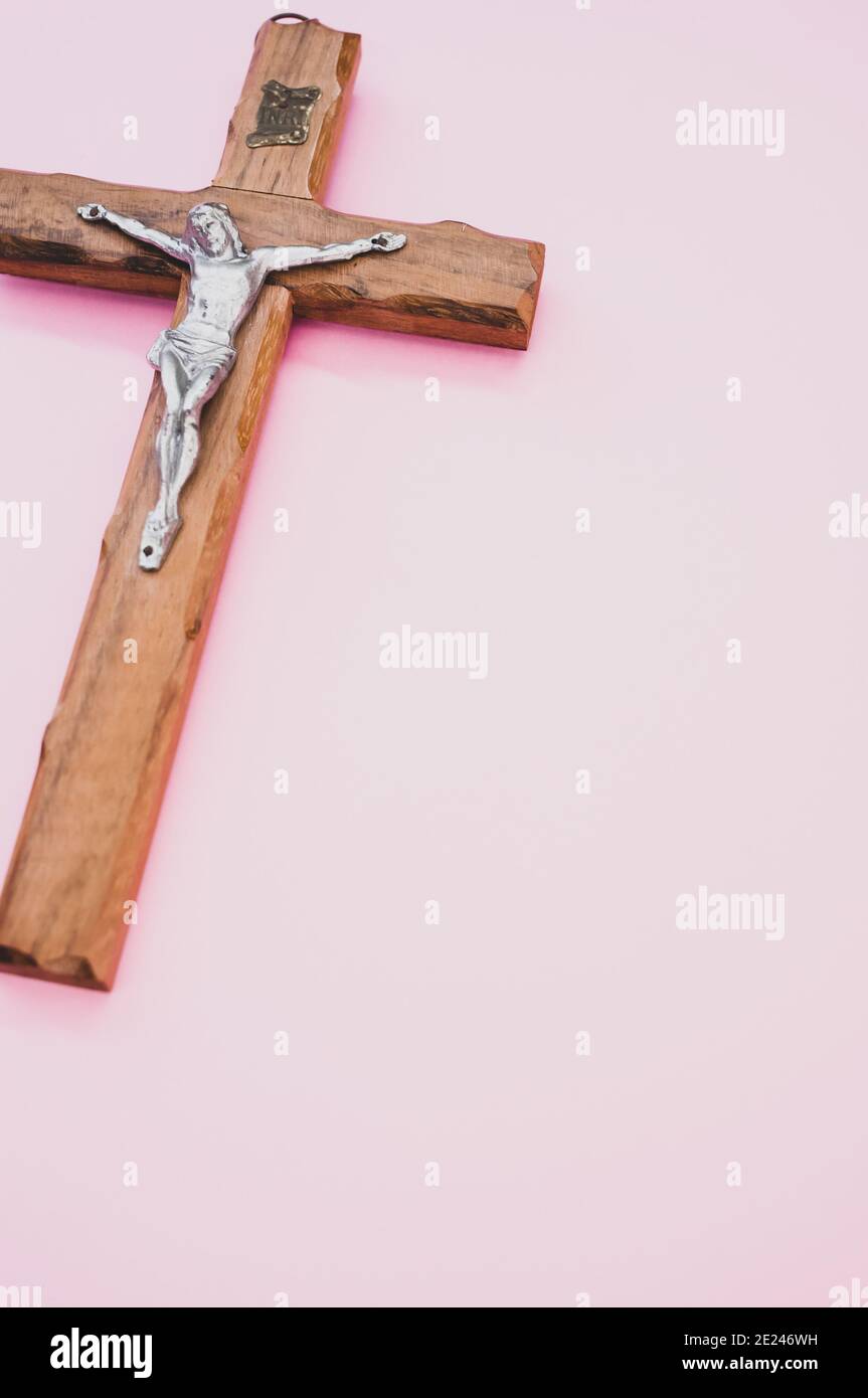 Vertical shot of a wooden crucifixion of Christ cross on a pink ...