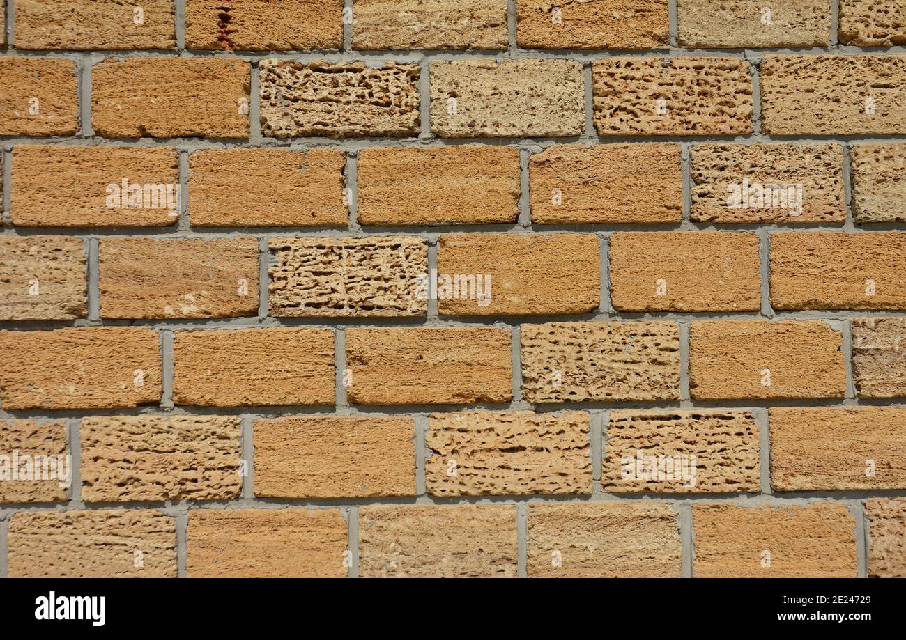 A close-up of an old yellow limestone, shell rock brick wall or fence ...
