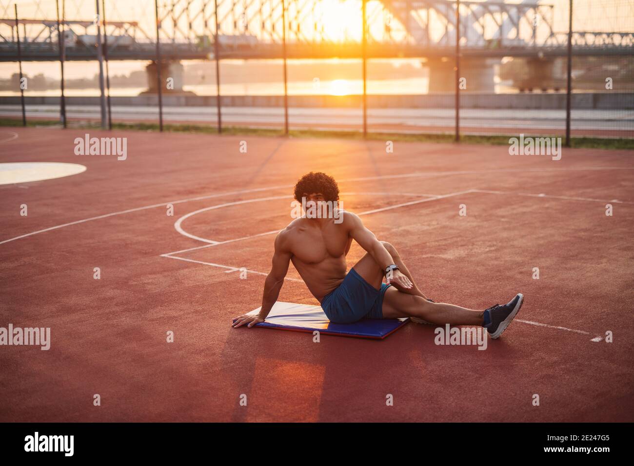 Young fit strong man stretching his muscles after hard training early ...
