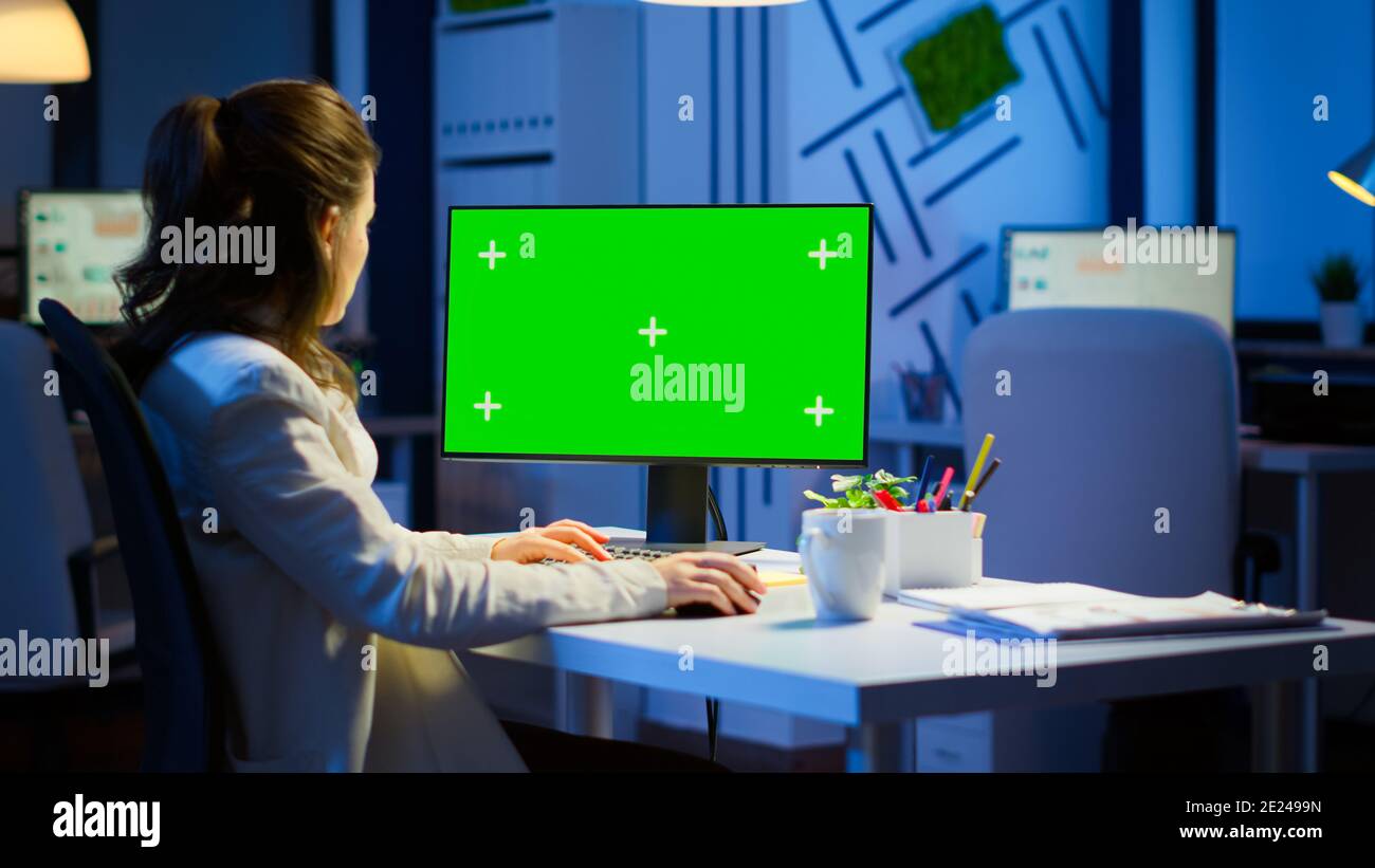 Businesswoman looking at green screen monitor of computer sitting at ...