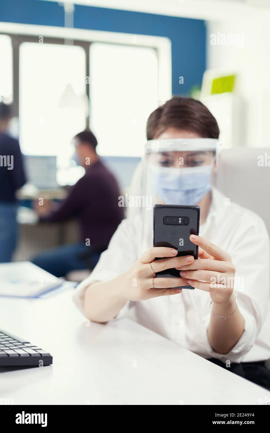 Businesswoman using mobile phone texting on smartphone wearing face ...