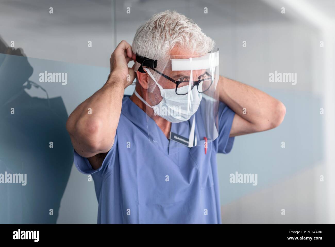 Doctor putting face shield on Stock Photo - Alamy