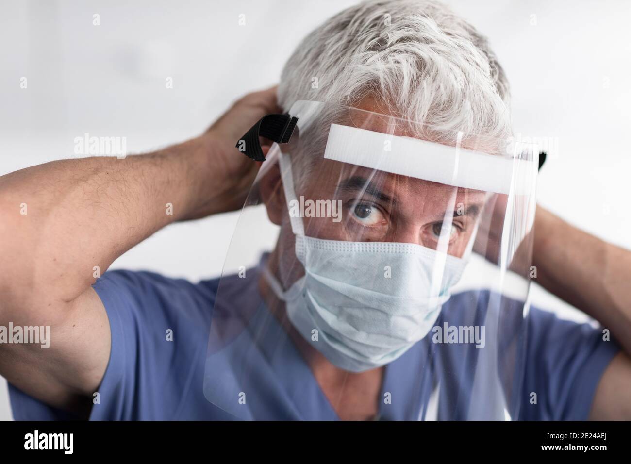 Doctor putting face shield on Stock Photo - Alamy