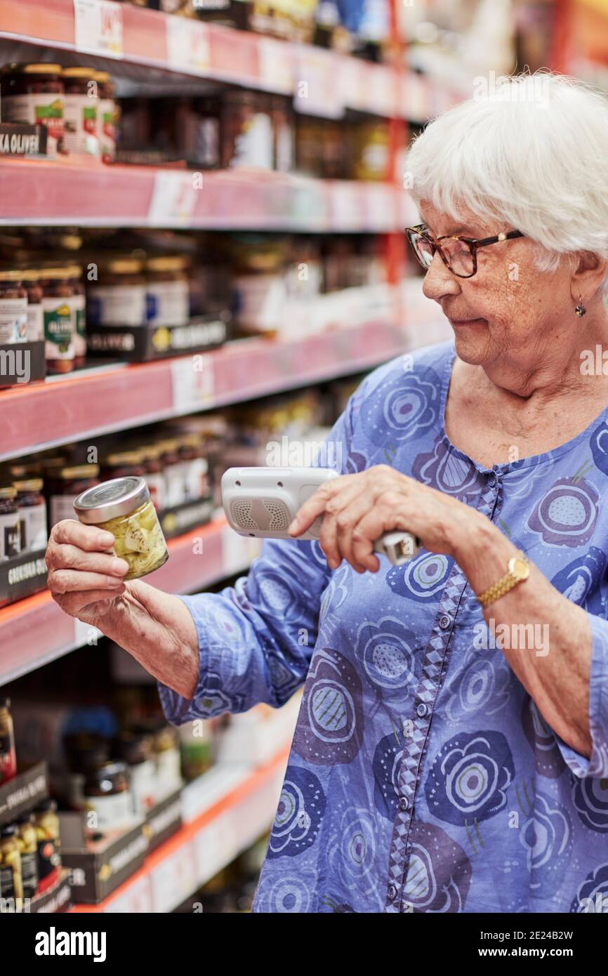 Senior woman using barcode reader in shop Stock Photo - Alamy
