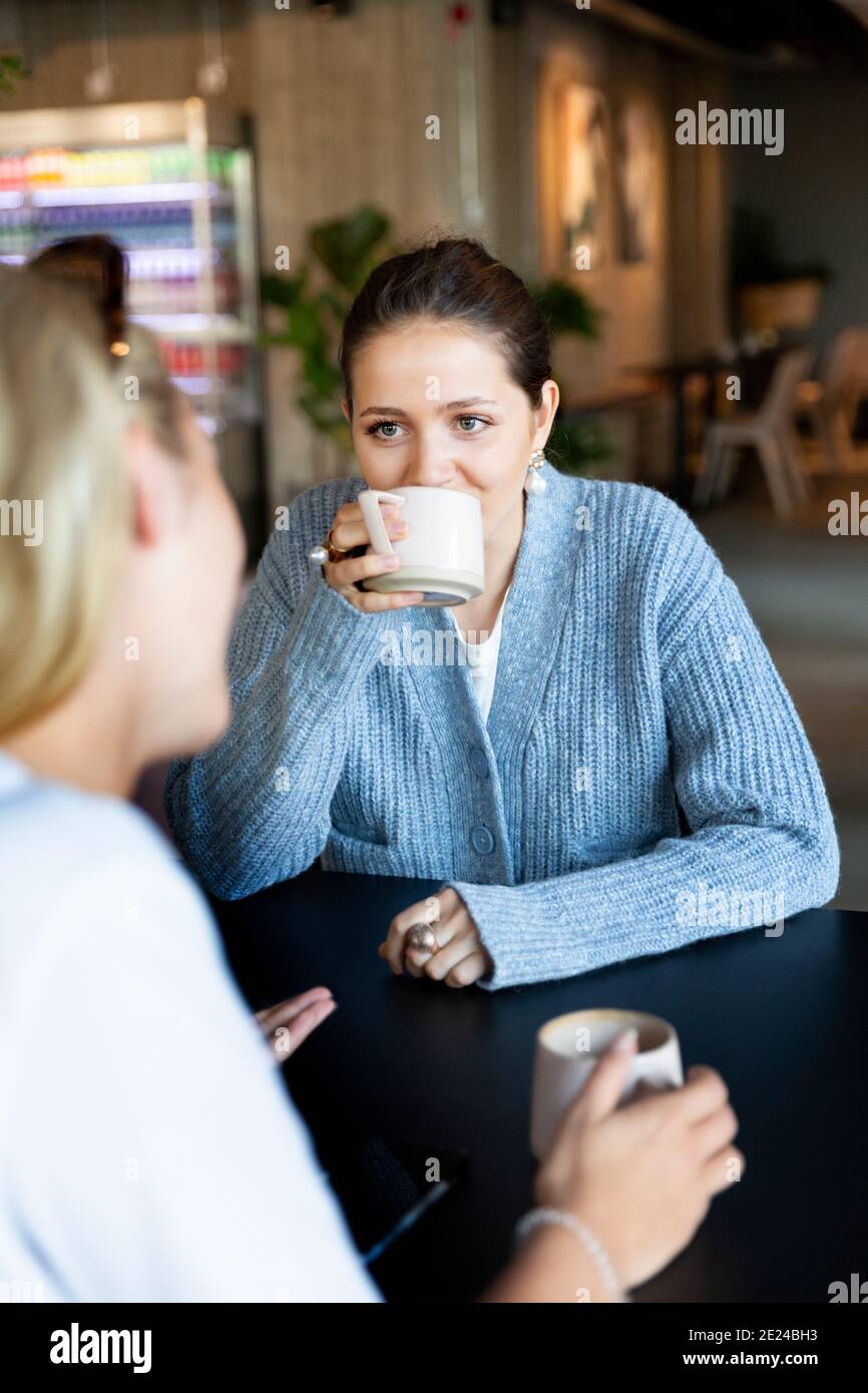 Smiling female friends talking in cafe Stock Photo - Alamy