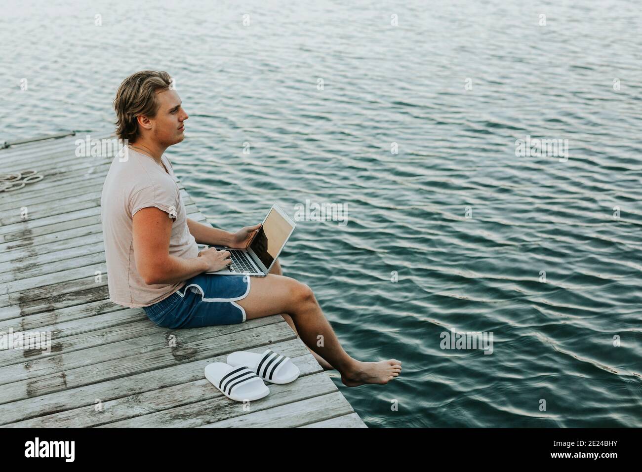 Young man sitting on jetty hi-res stock photography and images - Alamy