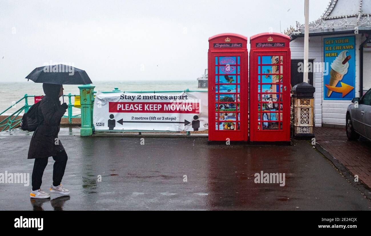 Brighton UK 12th January 2021 - It's wet and windy for this walker by ...