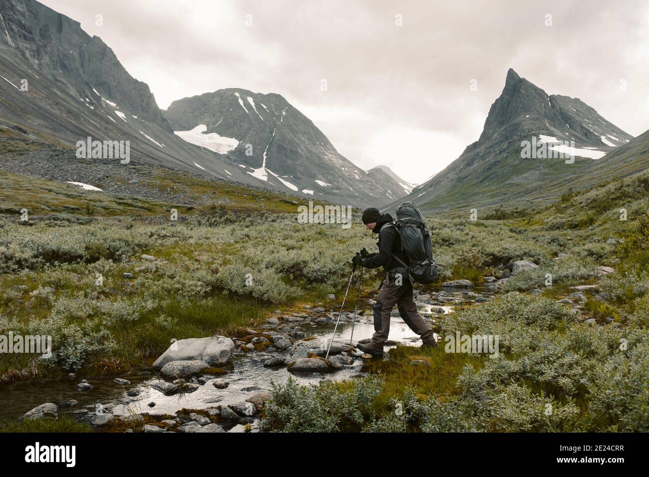 Hiker crossing stream in mountains Stock Photo - Alamy