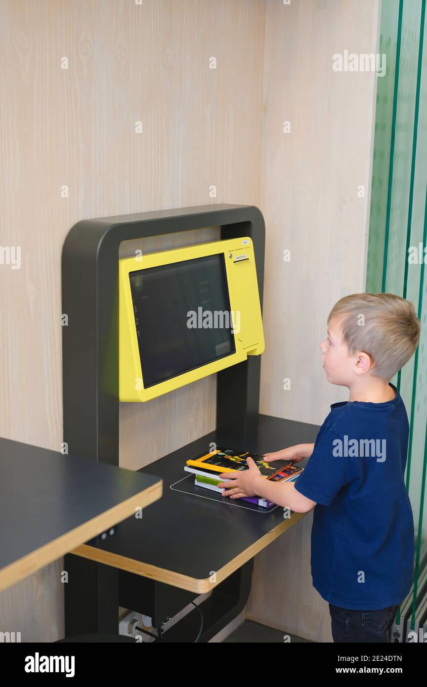 Boy using self service point in library Stock Photo - Alamy