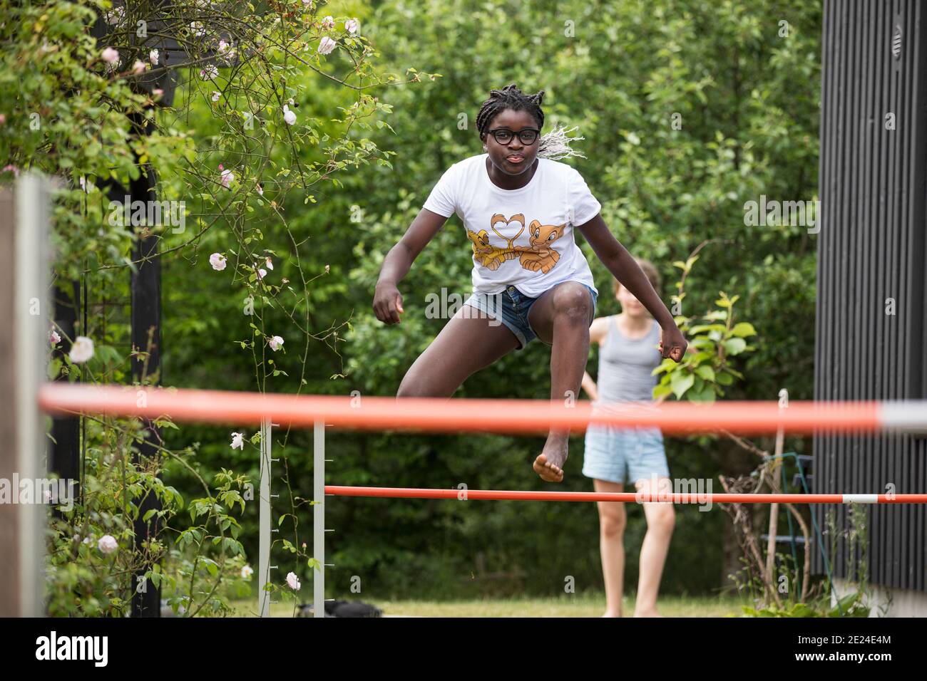 Girl jumping over hurdle Stock Photo - Alamy