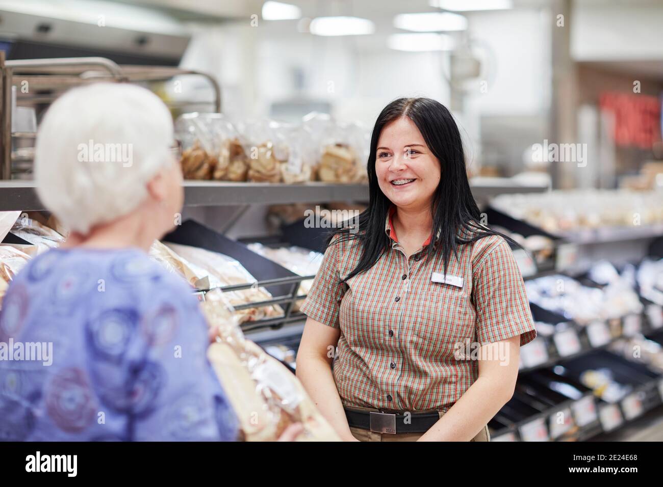 Woman in supermarket talking to store clerk Stock Photo - Alamy