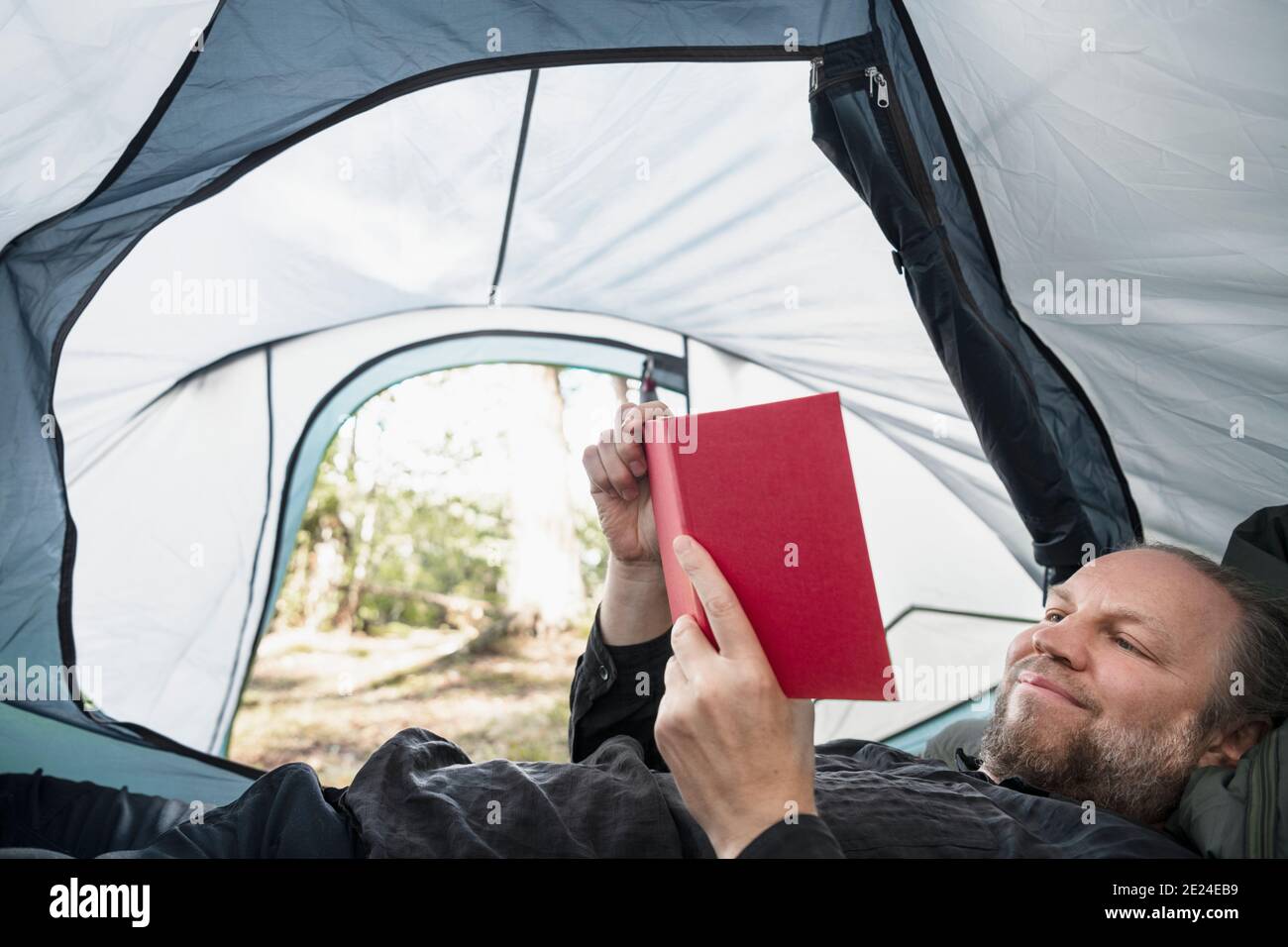 Man reading book in tent Stock Photo - Alamy