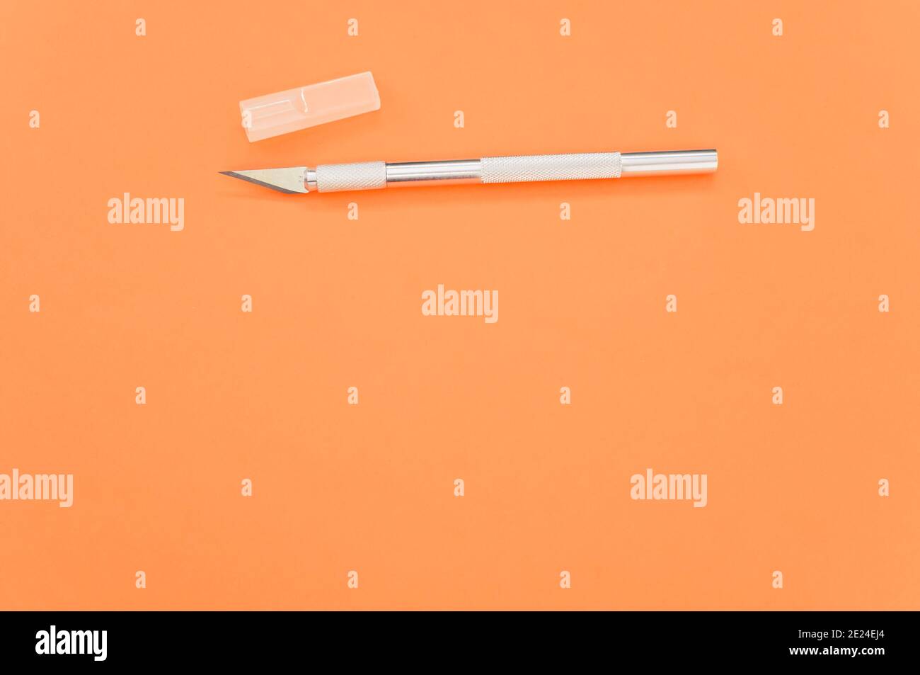 Top view of metallic scalpel with cap isolated on orange background ...