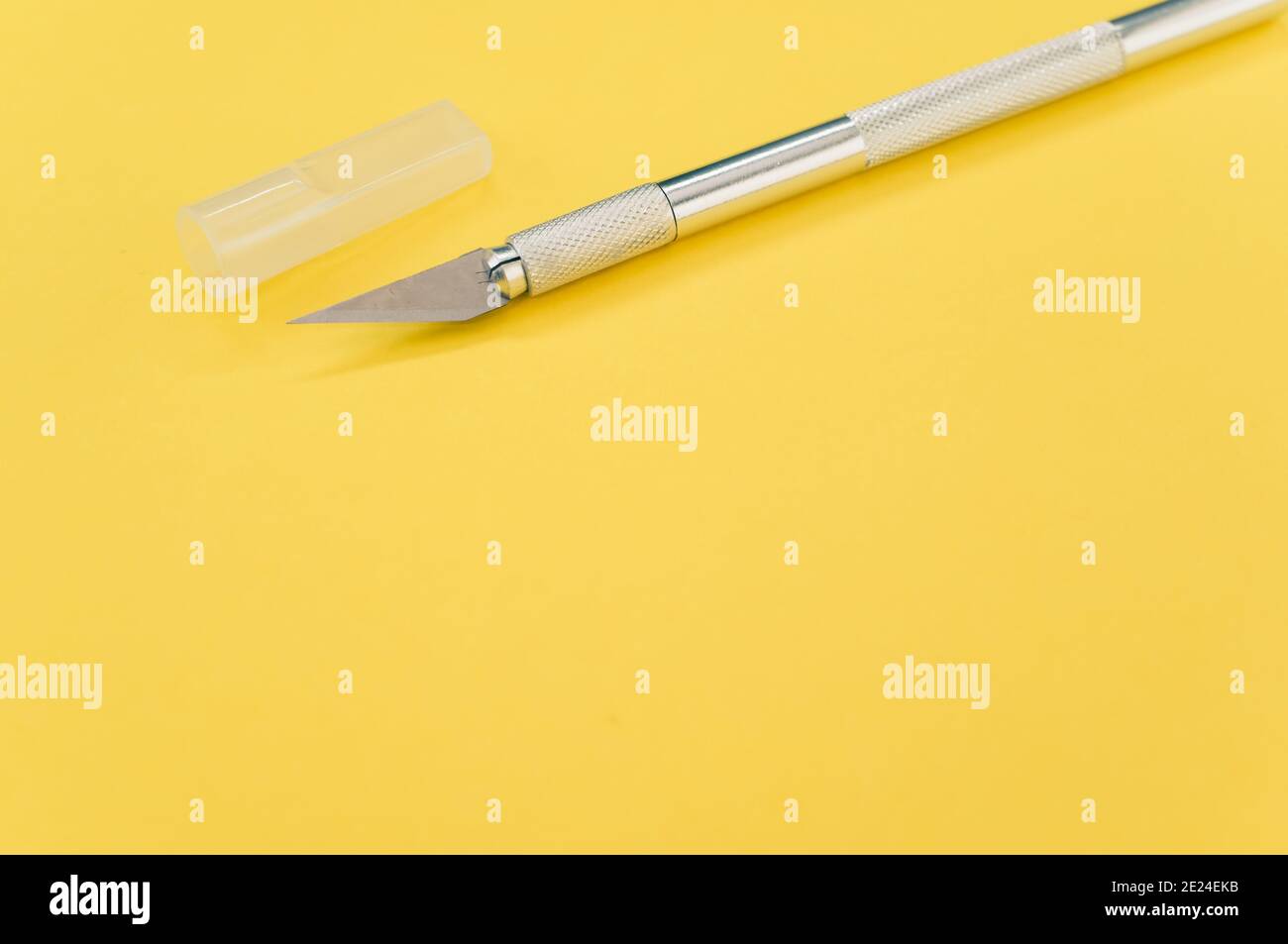 High angle shot of metallic scalpel with cap isolated on yellow ...