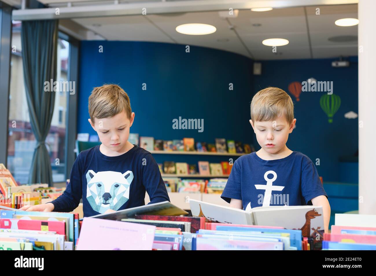 Boys looking at books in library Stock Photo - Alamy