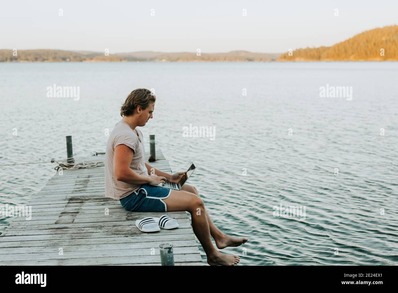 Young man sitting on jetty hi-res stock photography and images - Alamy