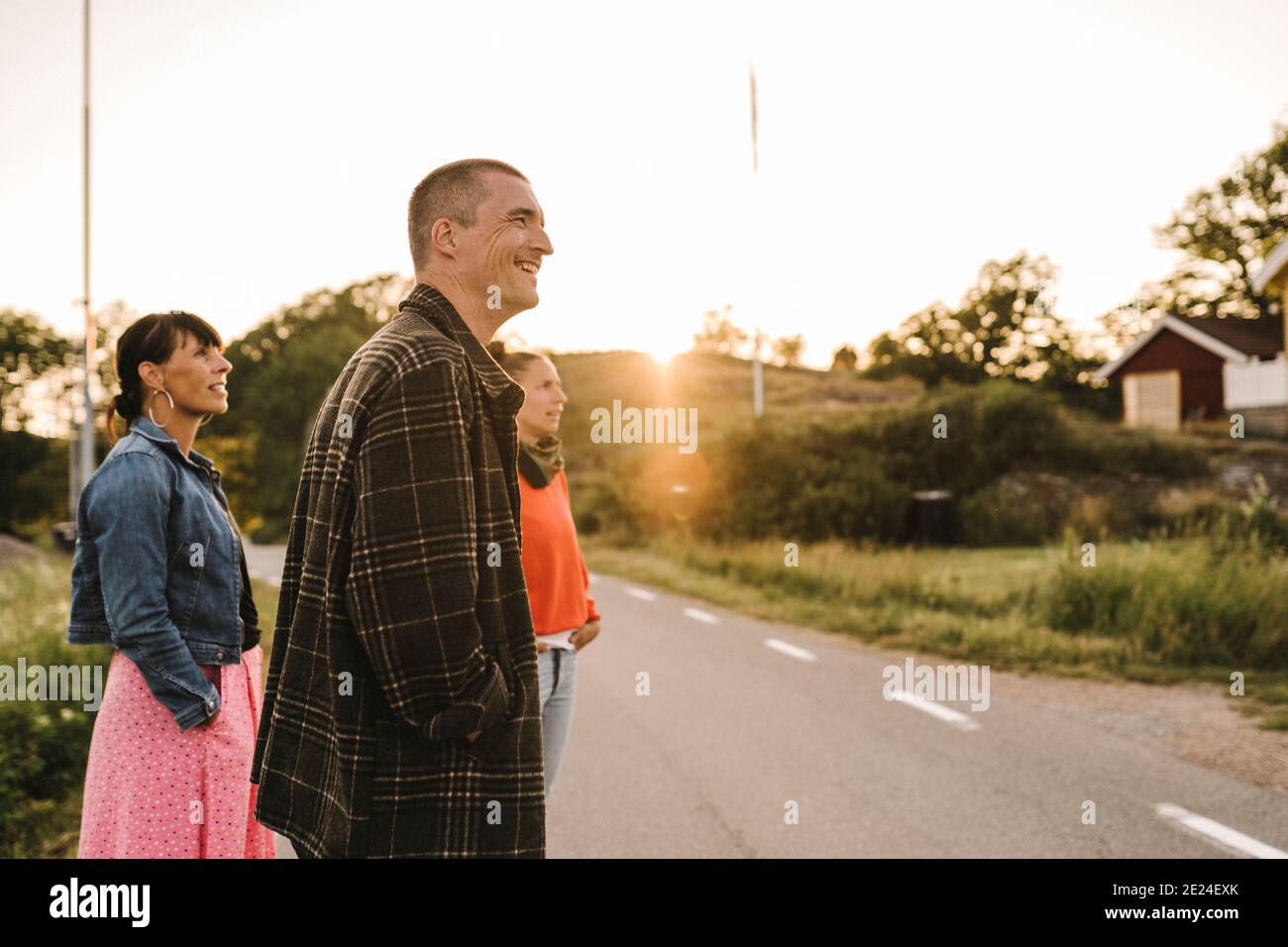 Smiling friends standing at roadside Stock Photo - Alamy