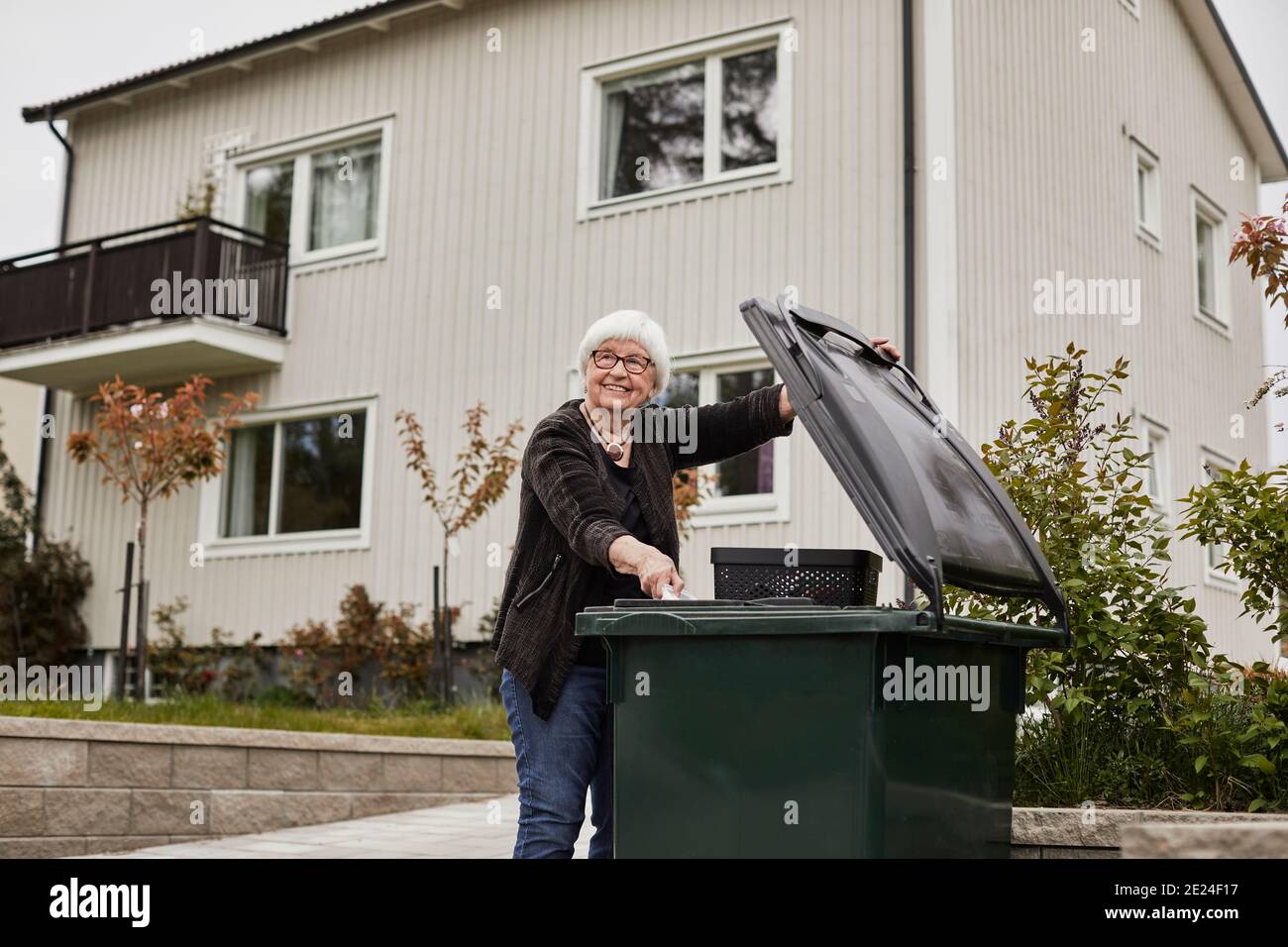 Woman putting rubbish into bin Stock Photo - Alamy