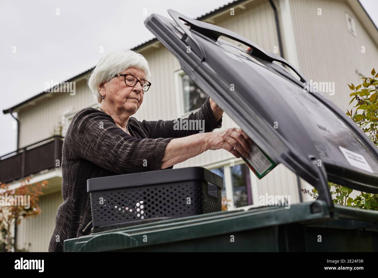 Woman putting rubbish into bin Stock Photo - Alamy