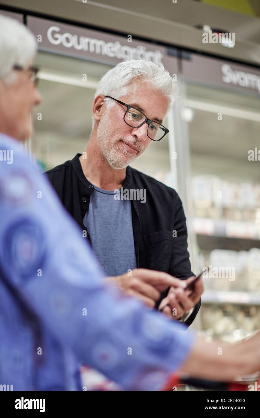 Man using cell phone in supermarket Stock Photo - Alamy