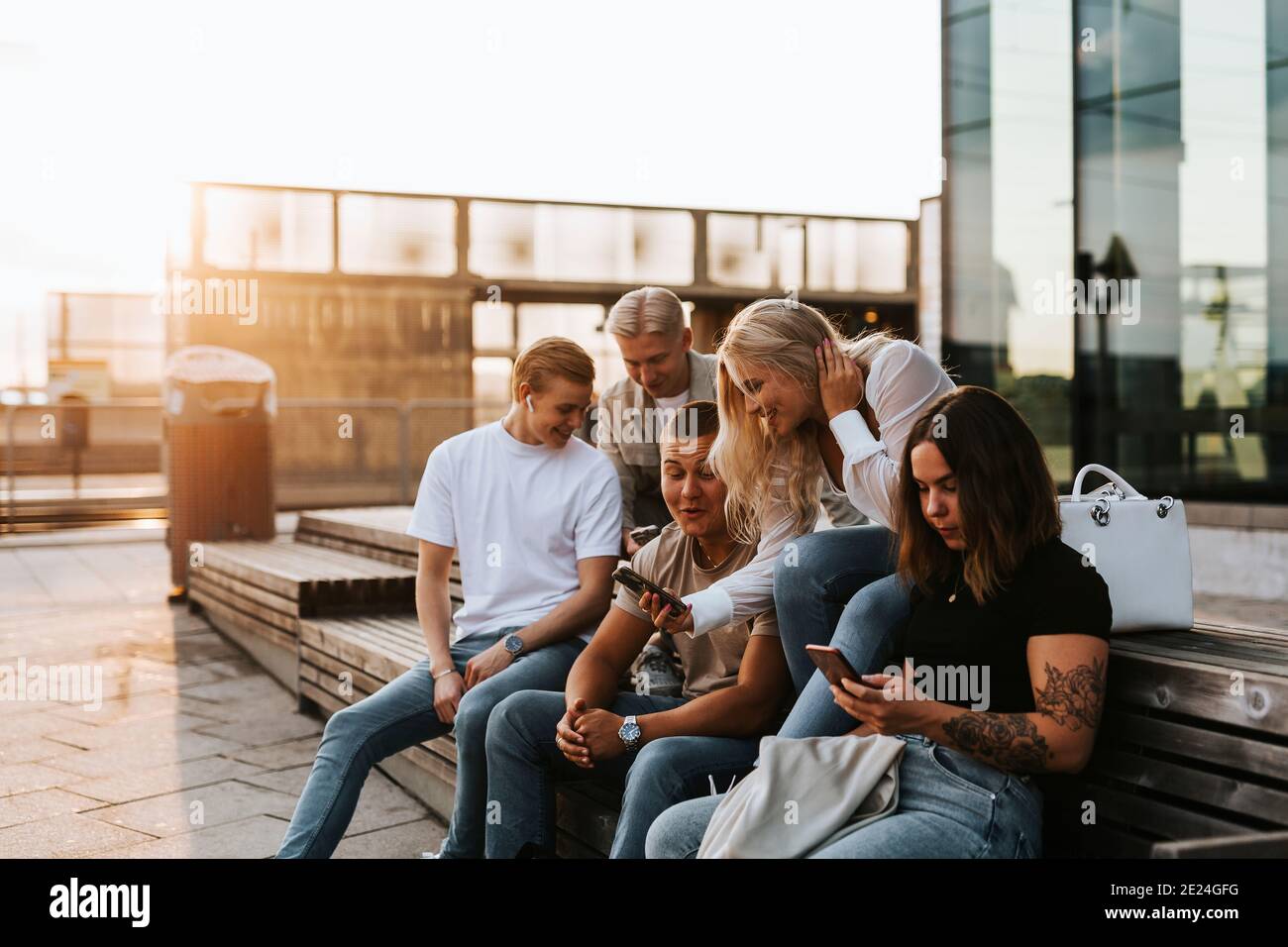 Smiling friends sitting on bench together Stock Photo - Alamy