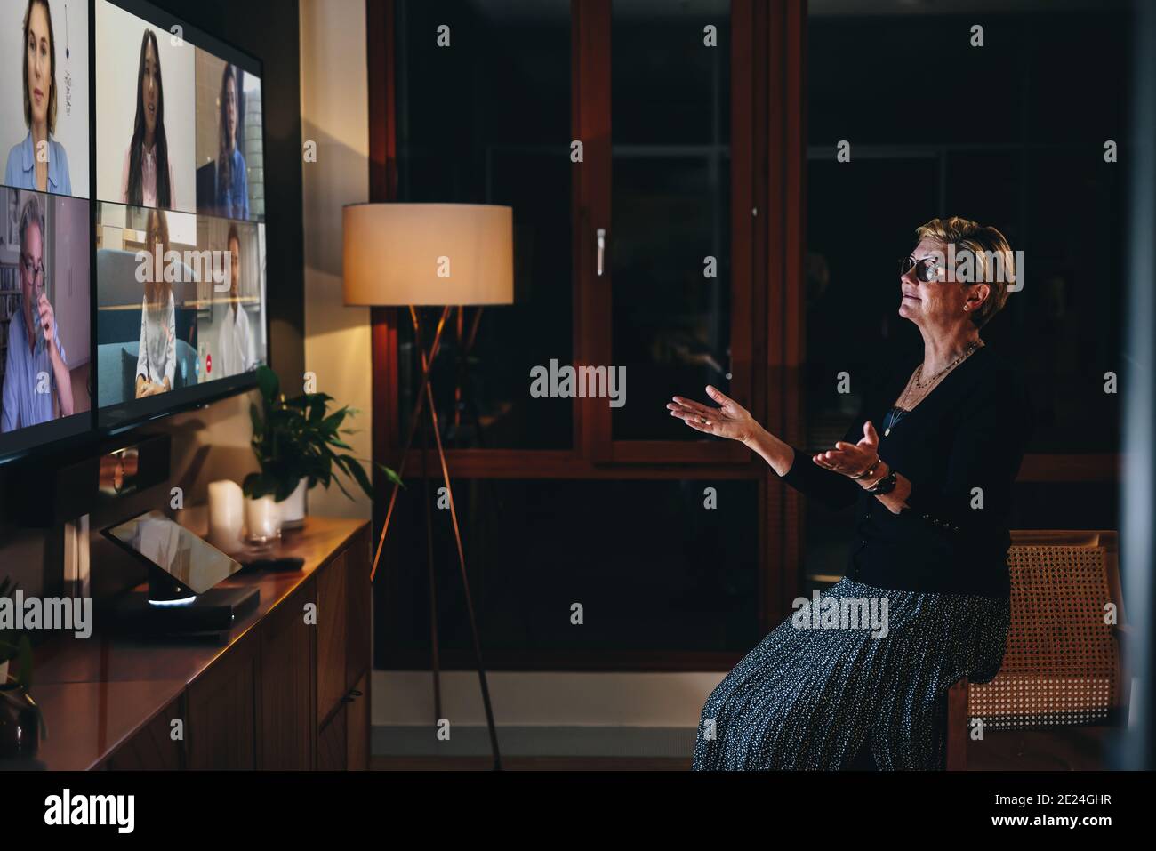 Mature business woman leading a confrence call late night. Multiracial ...