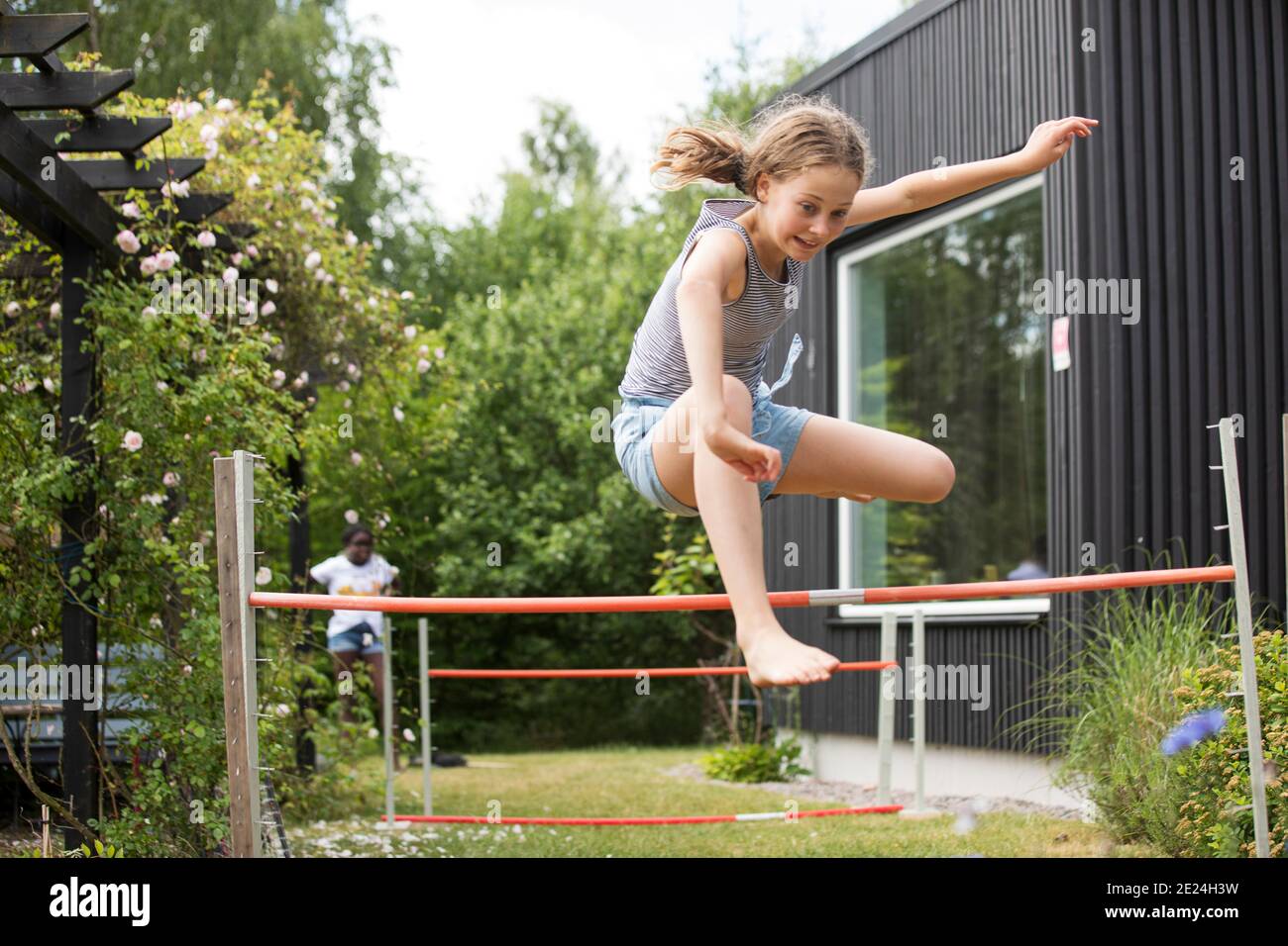 Girl jumping over hurdle Stock Photo - Alamy