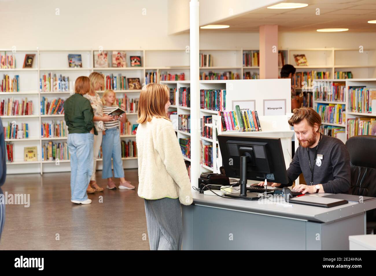 Girl talking to librarian in library Stock Photo - Alamy