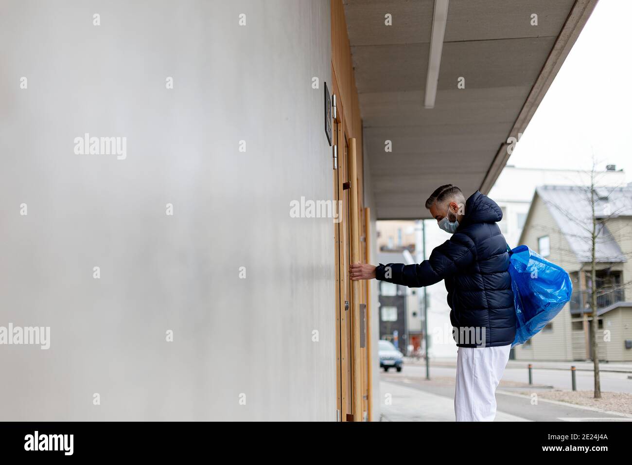 Man wearing face mask opening door Stock Photo - Alamy