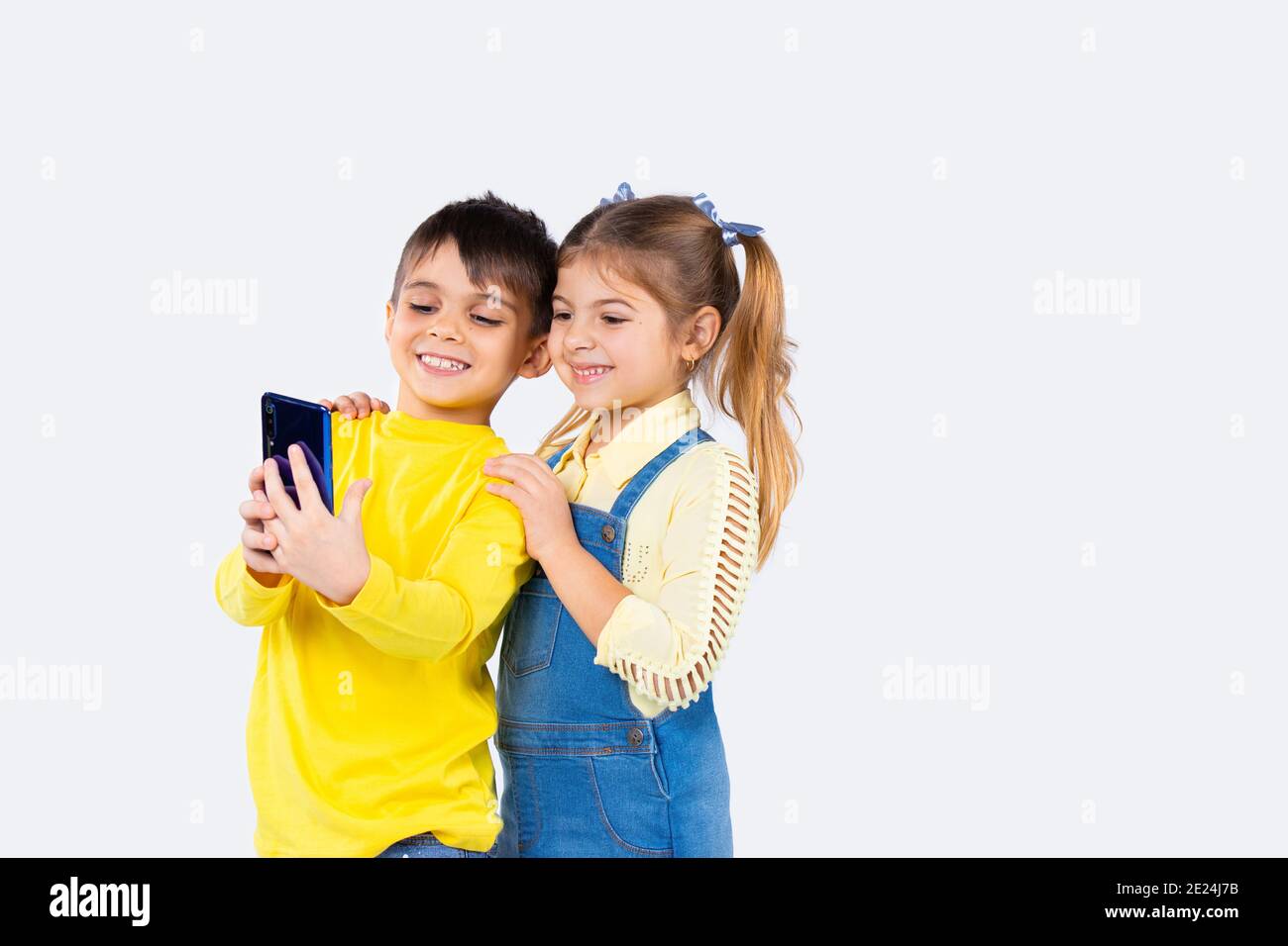 Happy preschool kids with smartphone video calling and smiling on white ...