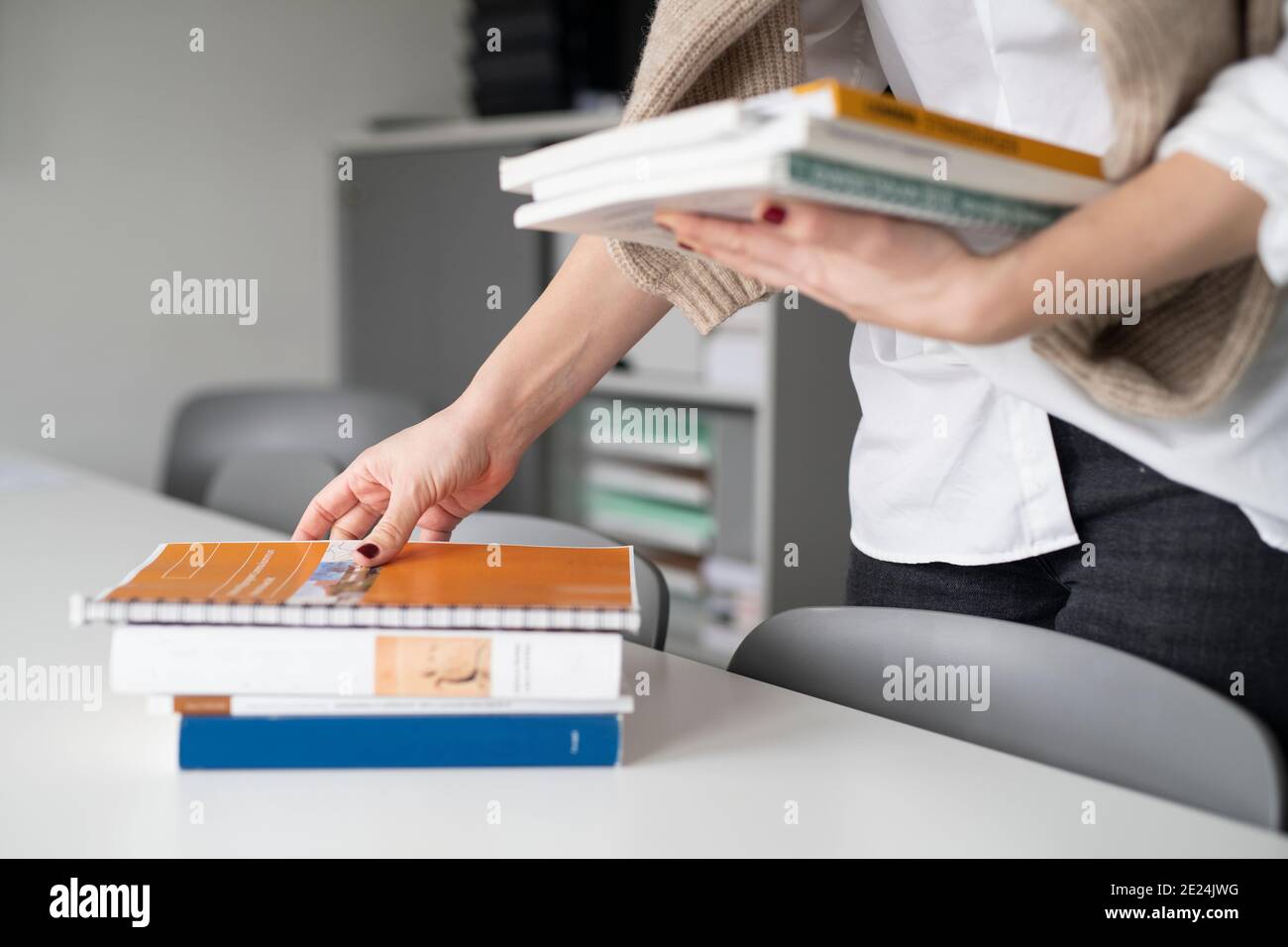 Woman picking up books Stock Photo - Alamy