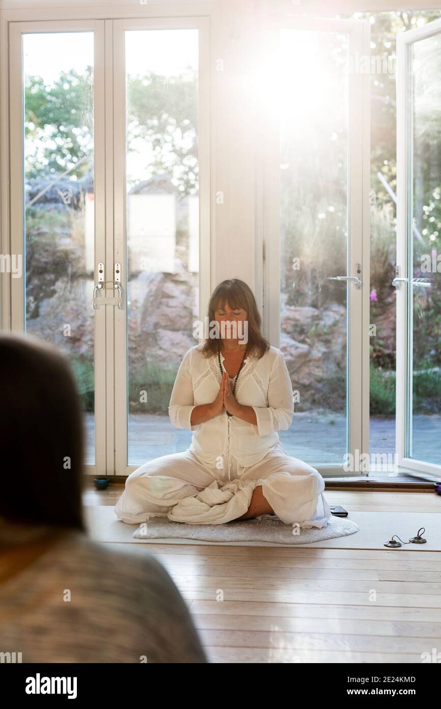 Yoga teacher sitting in front of class Stock Photo - Alamy