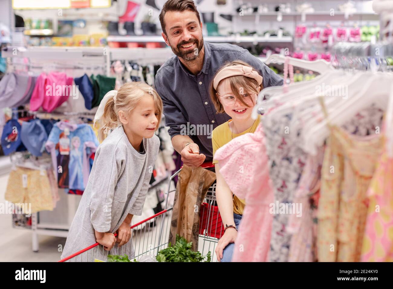Father with daughters looking at clothes in supermarket Stock Photo - Alamy