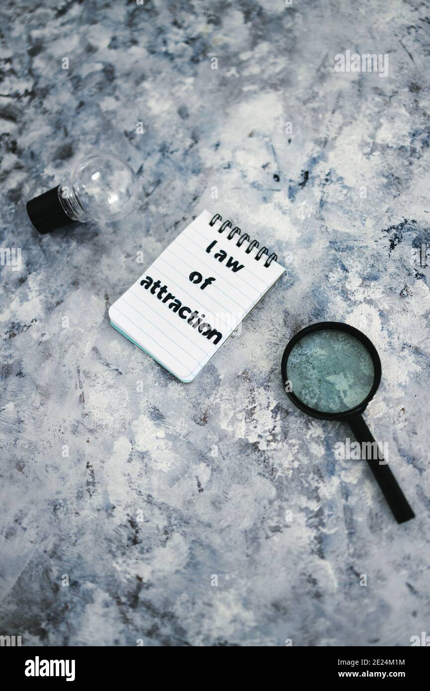 law of attraction notepad with text next to light bulb and magnifying ...