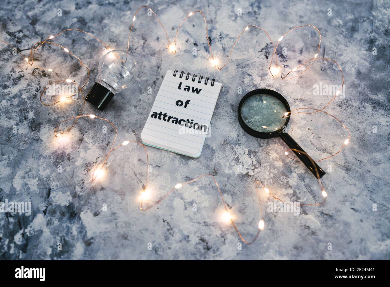 law of attraction notepad with text next to light bulb and magnifying ...