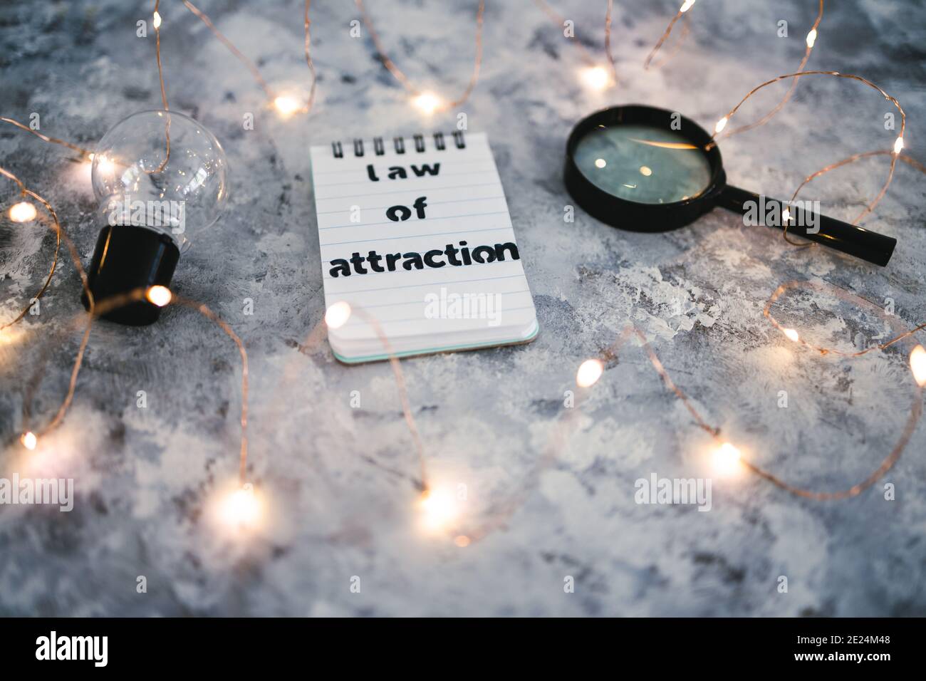law of attraction notepad with text next to light bulb and magnifying ...