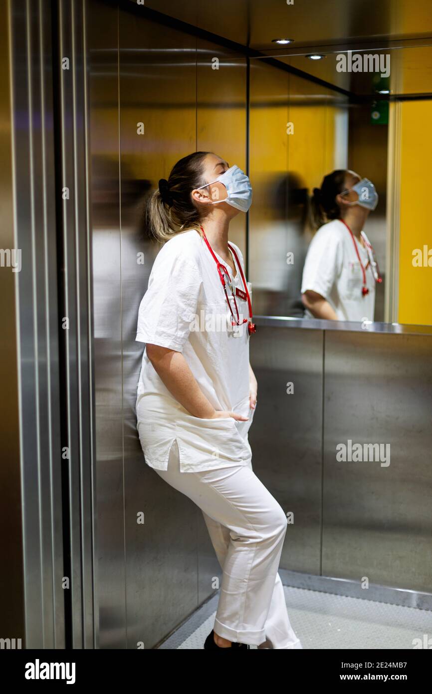 Tired female doctor standing in lift Stock Photo - Alamy