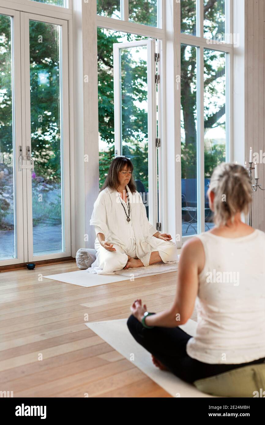 Yoga teacher sitting in front of class Stock Photo - Alamy