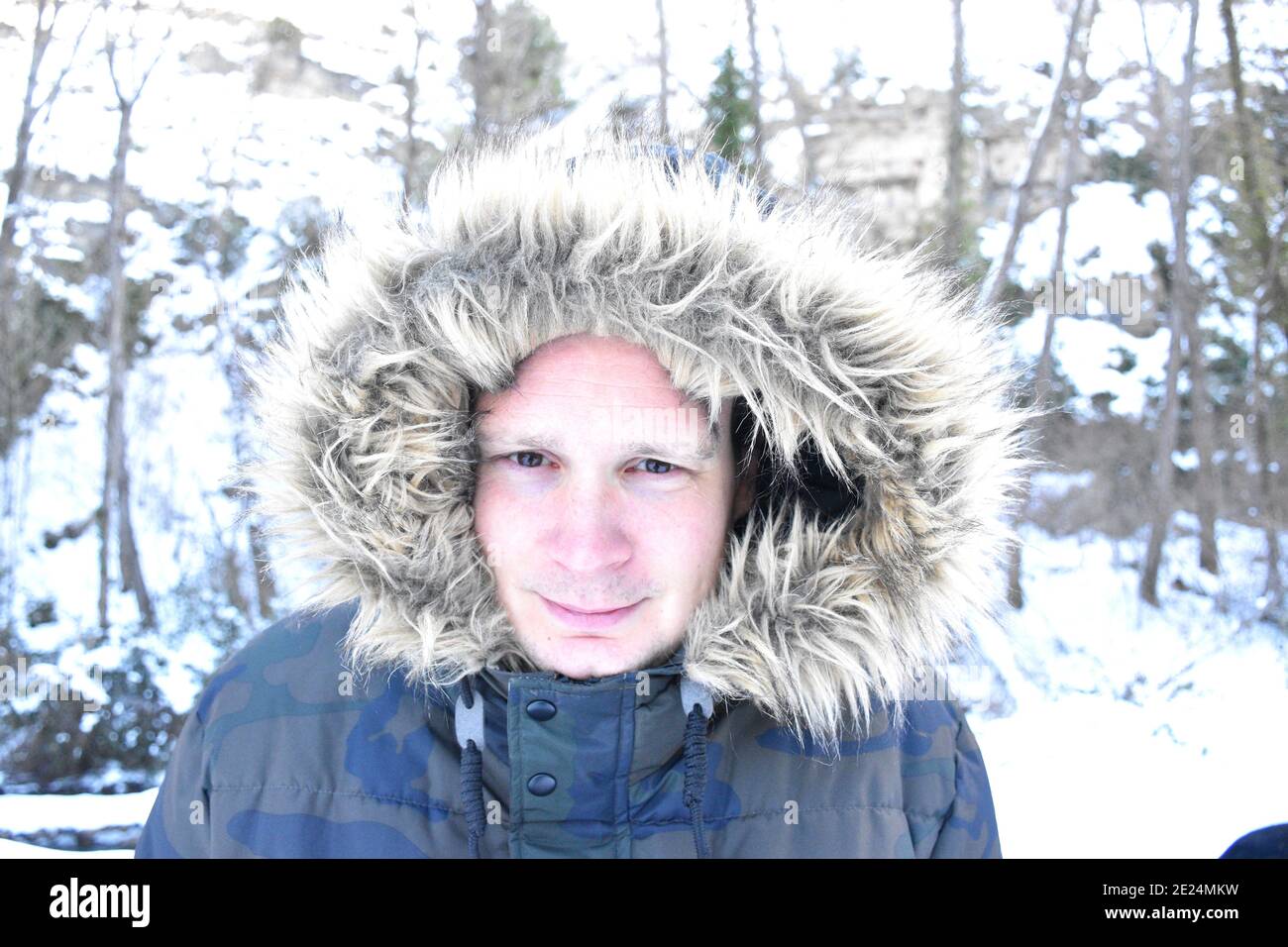 Portrait of man without beard with hood with hair in snowy area. Scene ...